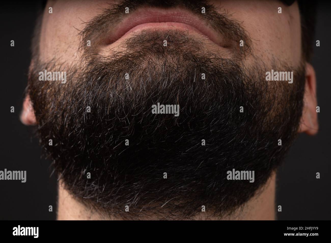 Portrait of a young bearded man face looking up, chin view from below ...