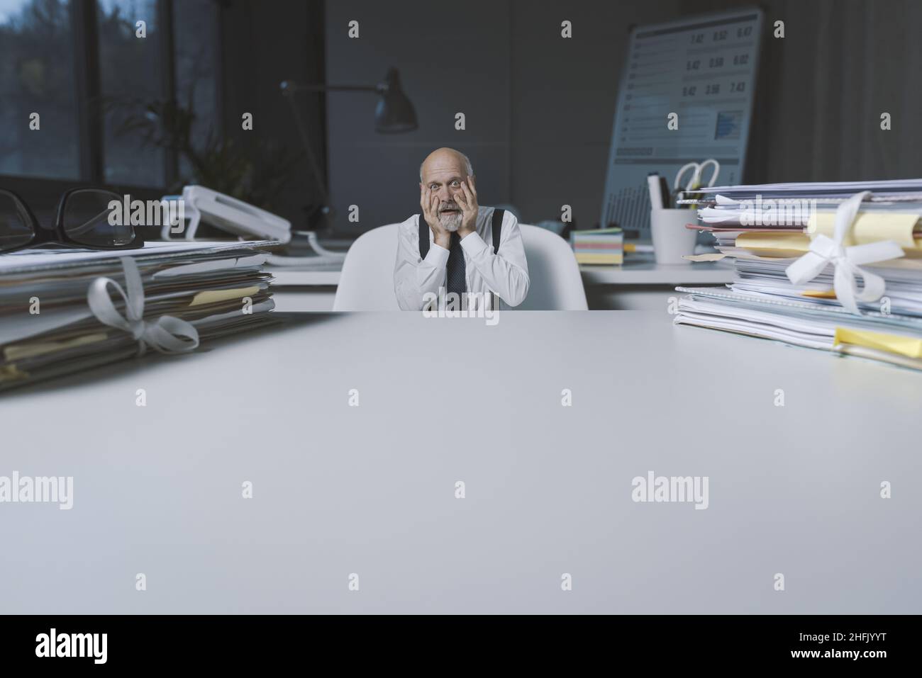 Stressed terrified businessman sitting at office desk and working ...