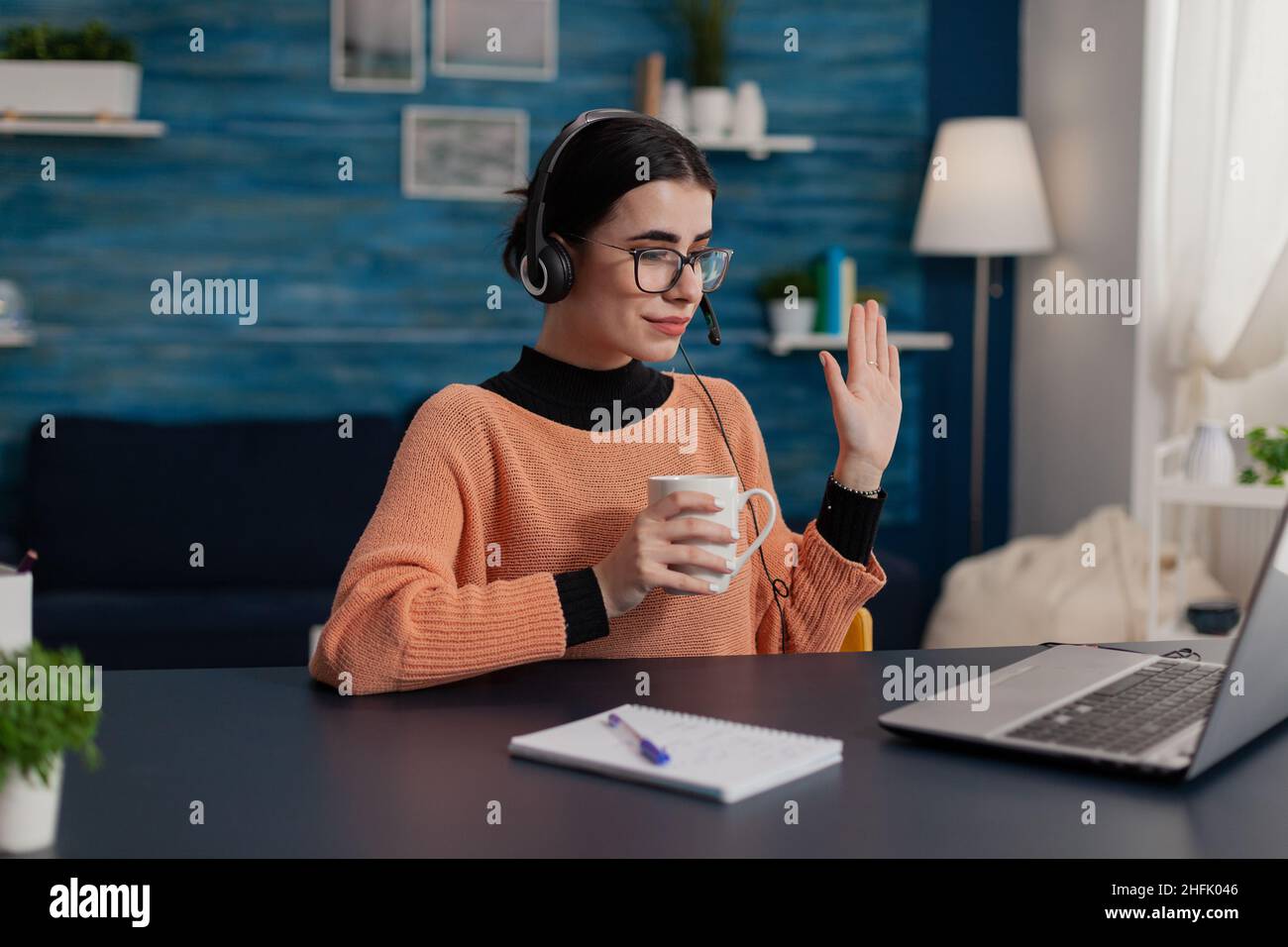 Student with headphones waving hello in laptop videocall. College girl ...