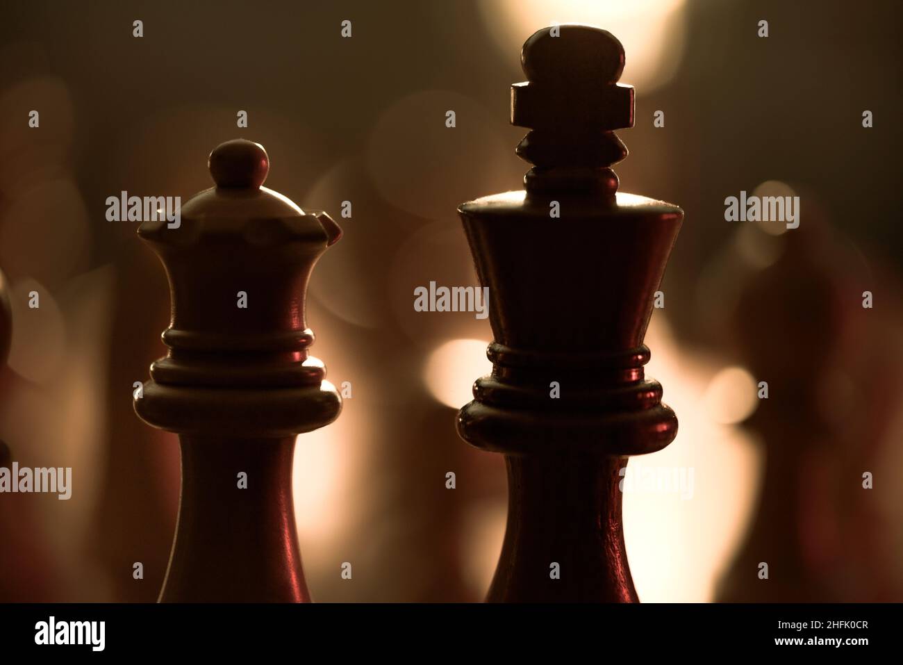 Wooden chess pieces on the chessboard and golden dim light with bokeh ...