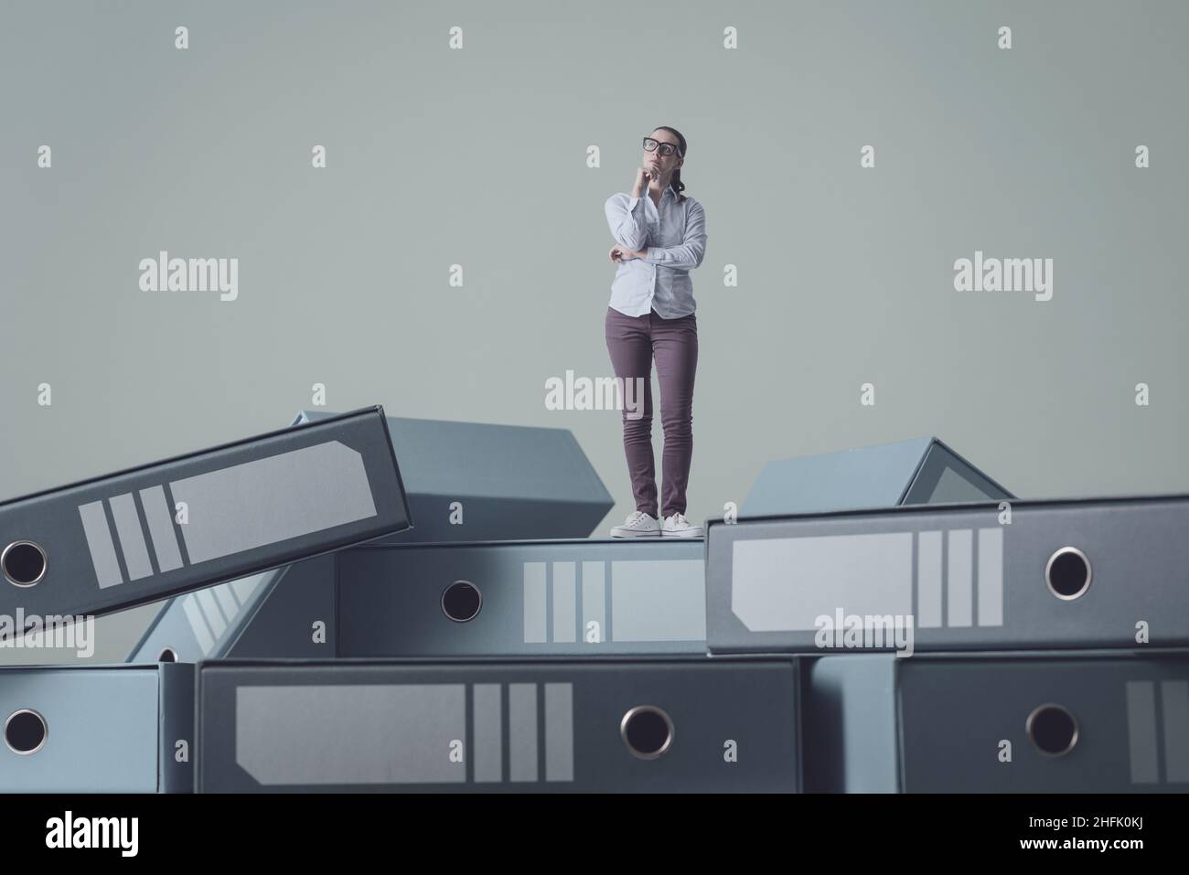 Businesswoman standing on a load of messy disorganized ring binders and ...