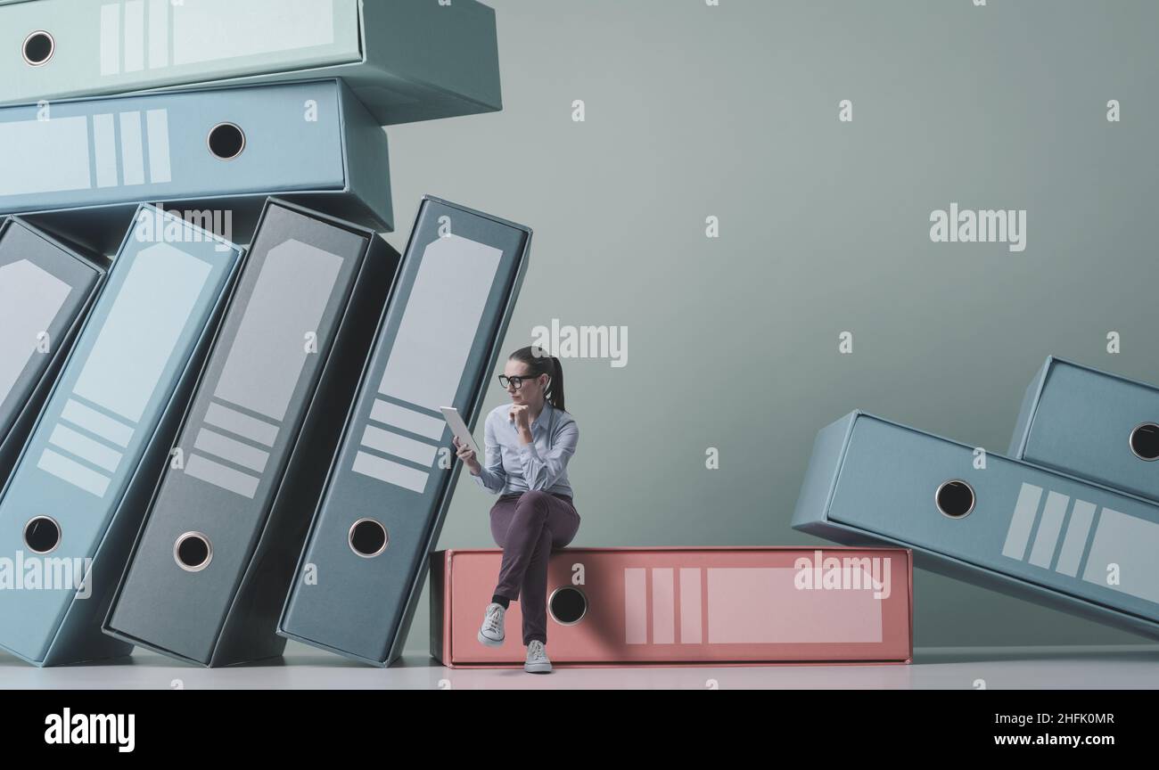 Woman connecting online and accessing information with her tablet instead of searching files in ...