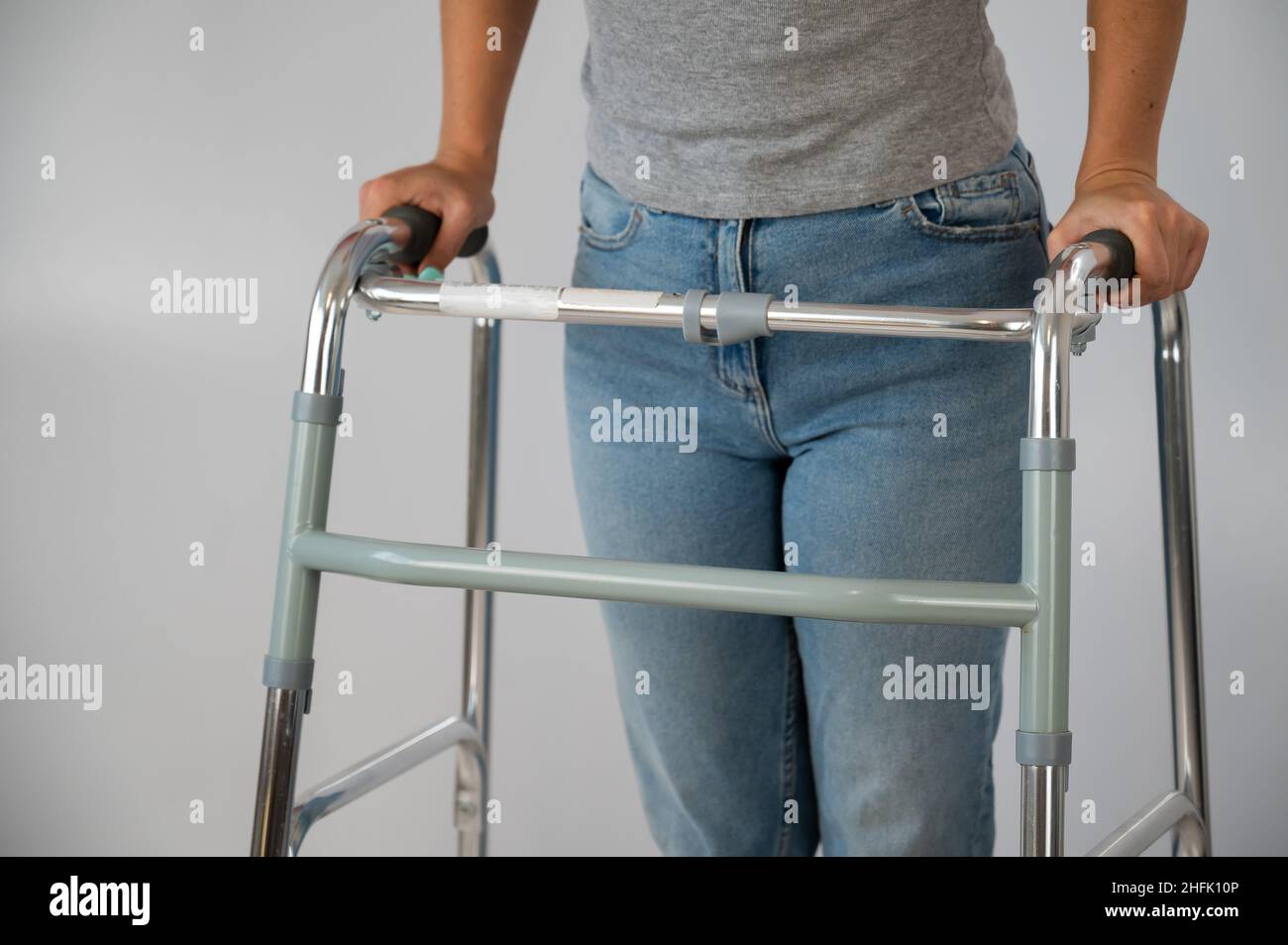 A woman is walking with a walker on a white background Stock Photo - Alamy