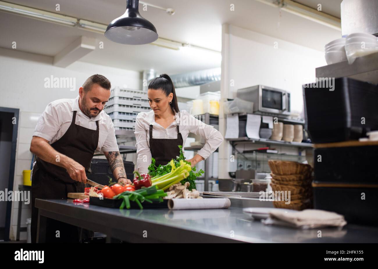 Chef teaching how to cook, cutting vegetables indoors in commercial ...