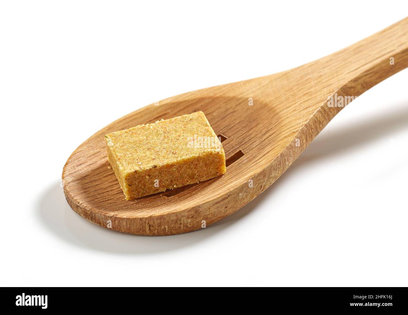instant chicken broth cube in wooden spoon isolated on white background ...
