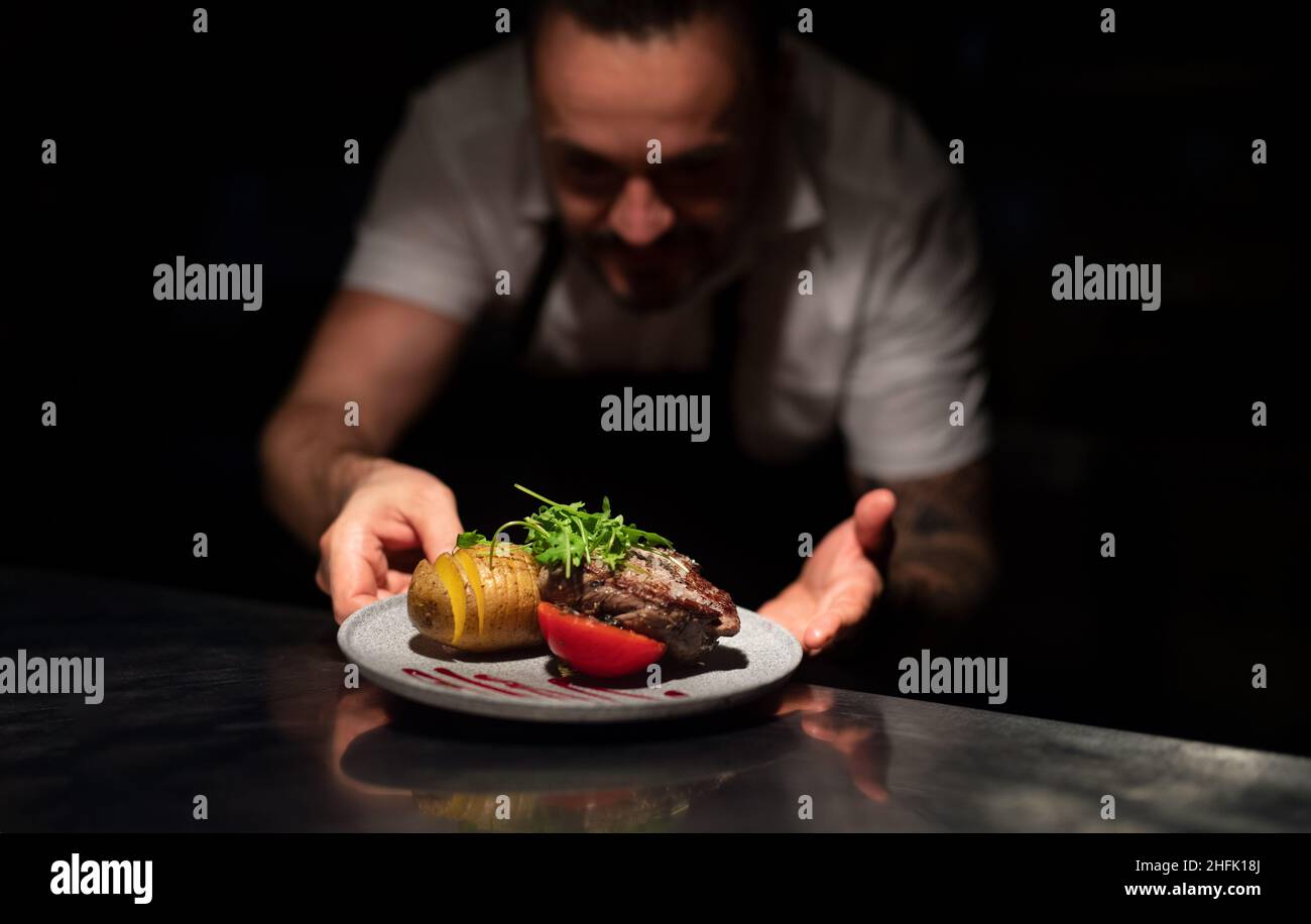 Chef handing plate with meal through order station in the commercial ...