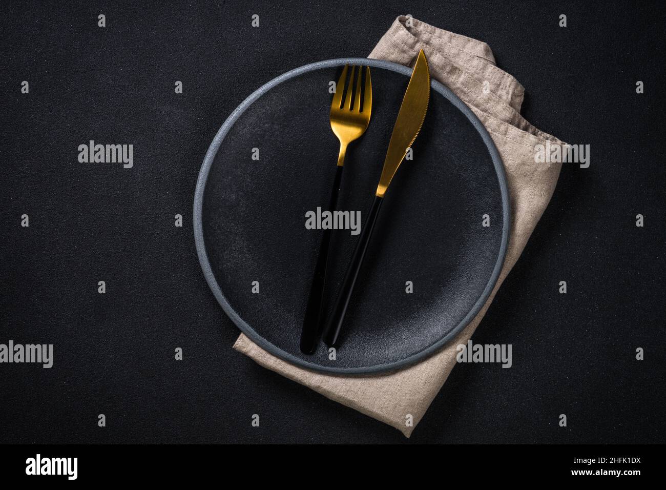 Table setting with black plate at black background Stock Photo - Alamy