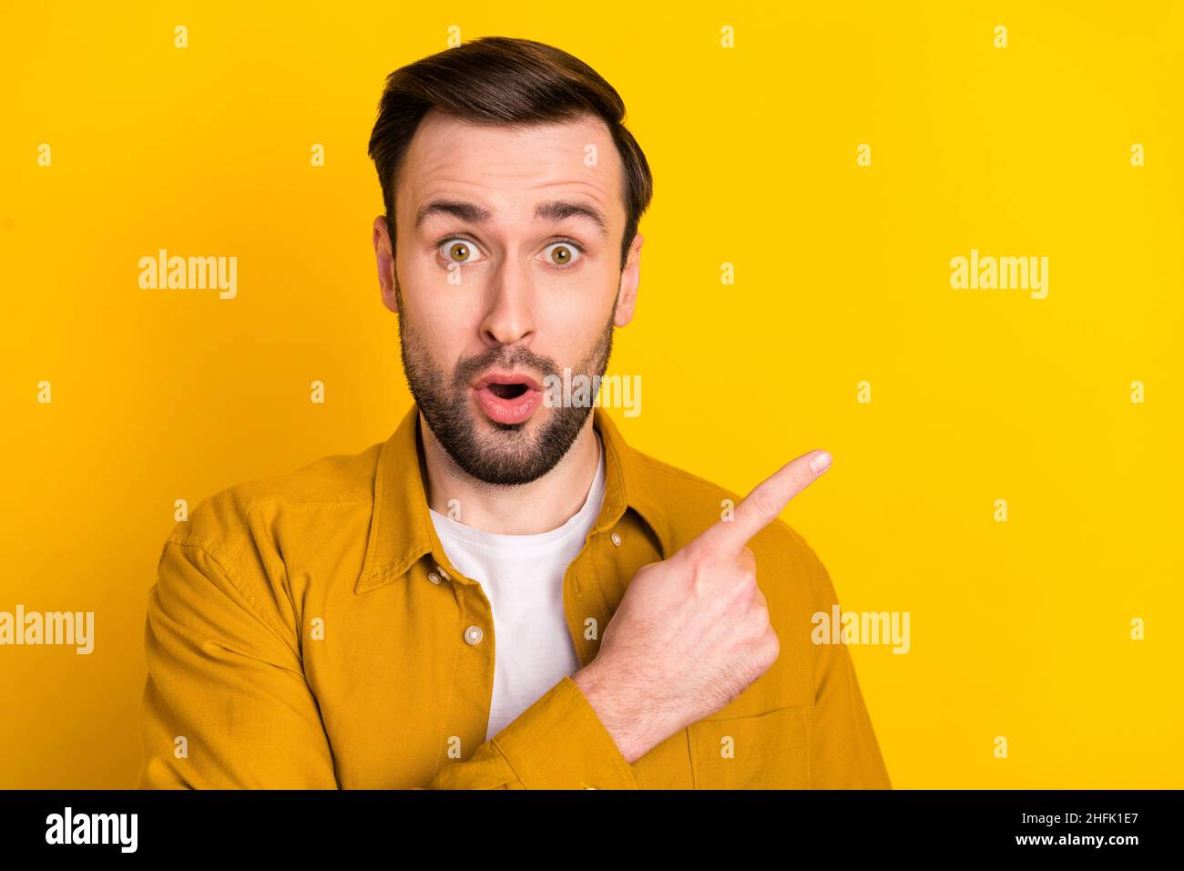 Photo of young handsome man amazed surprised point finger empty space ...