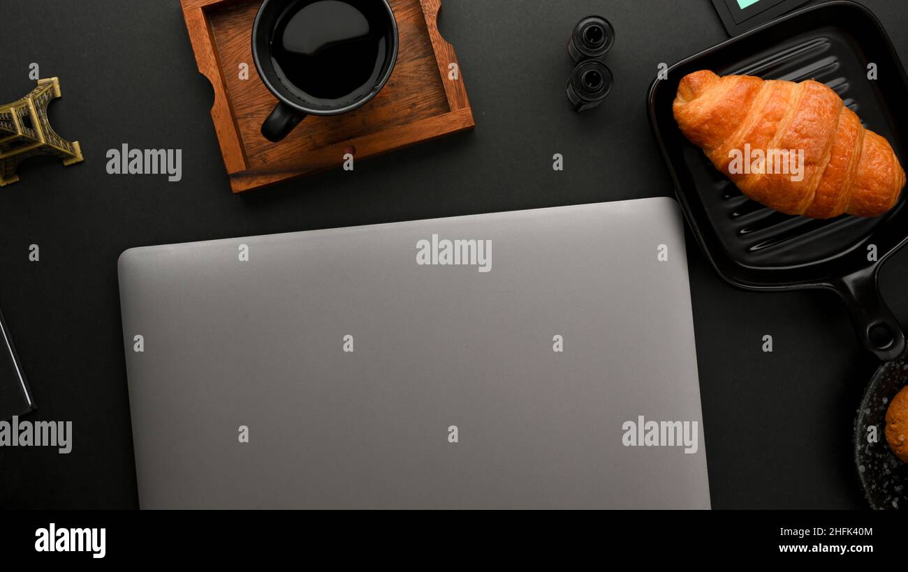 Minimal dark office desk with laptop computer, coffee and croissant on ...