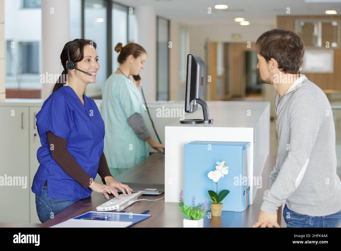professional receptionist working with patient at desk in modern clinic ...