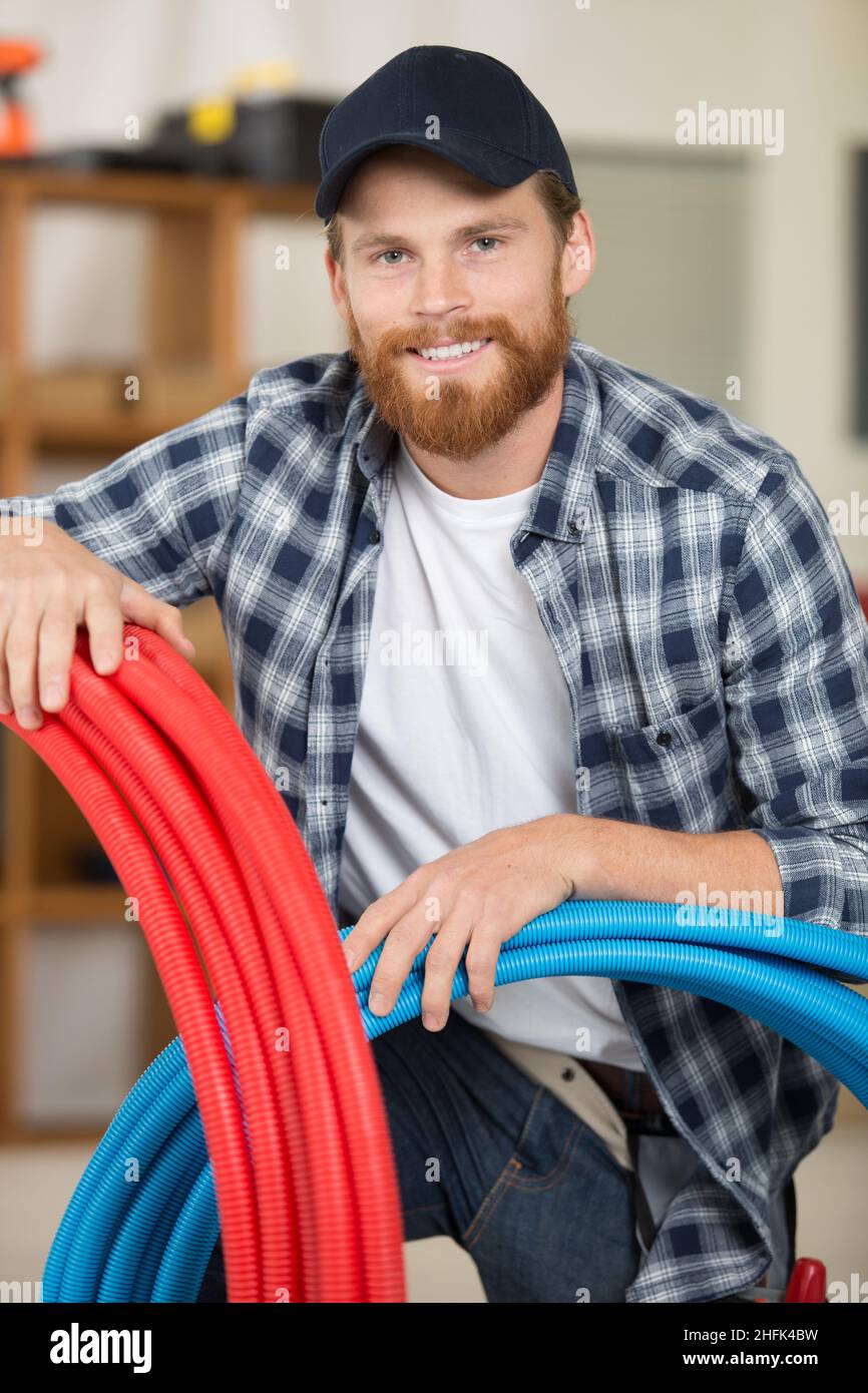 man with rolls of red and blue pipe Stock Photo - Alamy