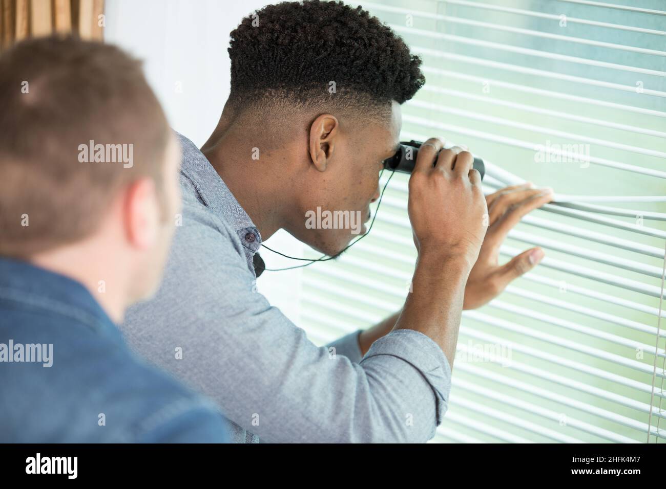 two men standing looking through a window Stock Photo - Alamy