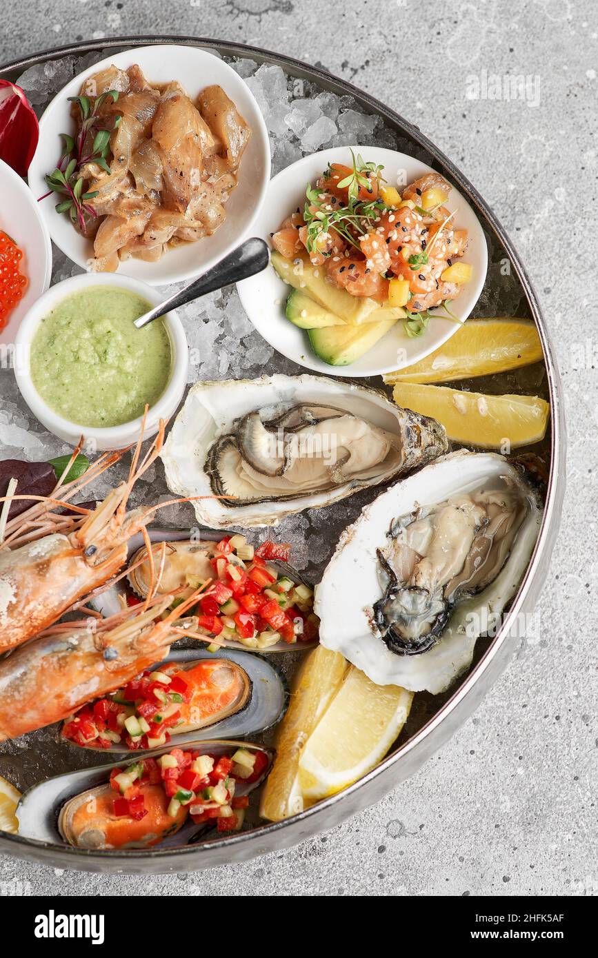 Metal tray with open oysters, raw mussels and caviar. Seafood ...