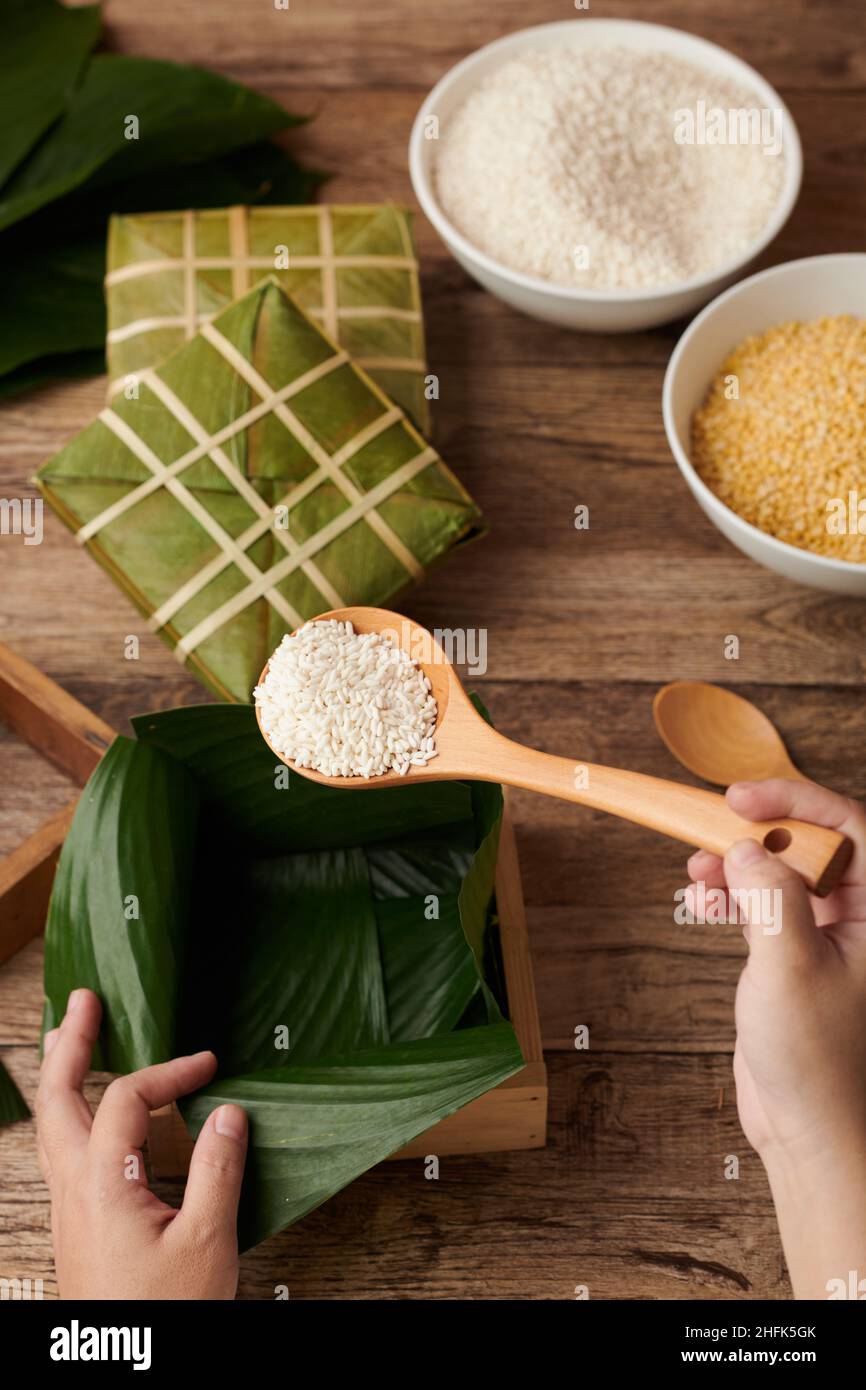 Hands putting white rice in box lined with lotus leaves when making ...