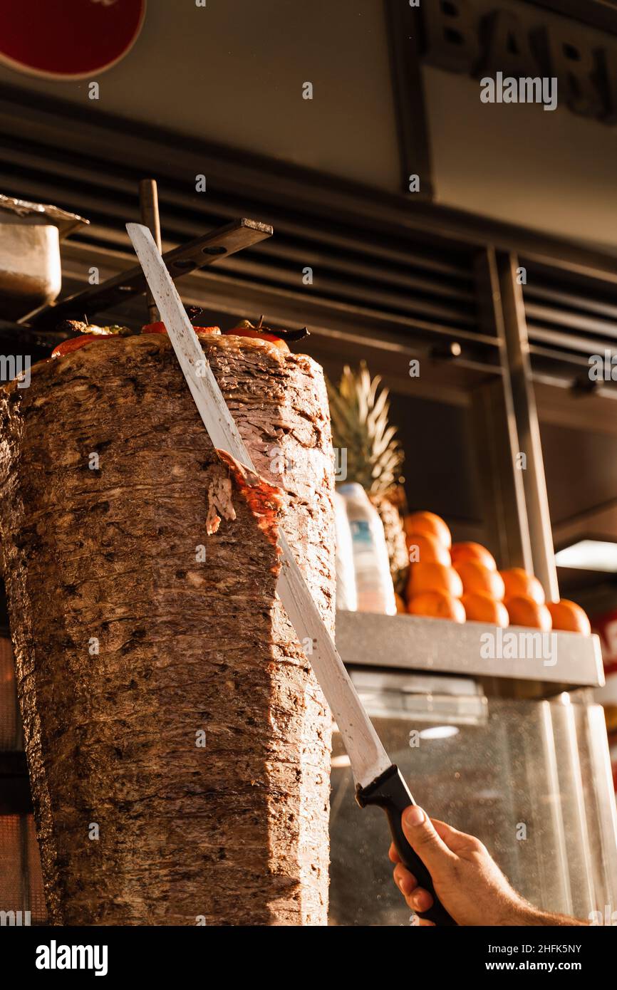 Cutting beef and lamb on a split for cooking doner kebab. Process of ...