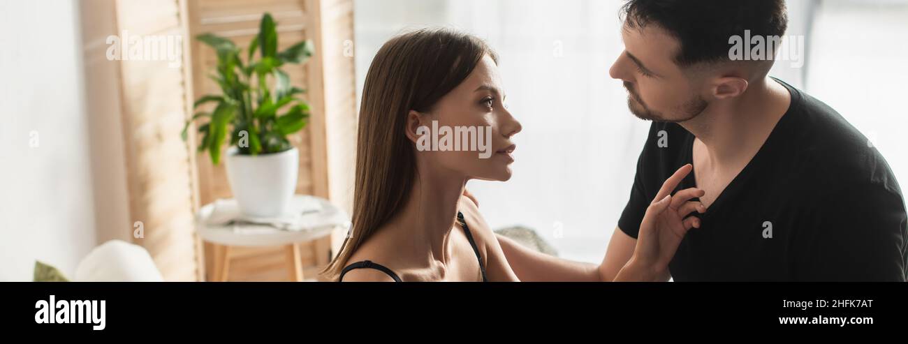 side view of young sensual woman looking at boyfriend in black t-shirt ...