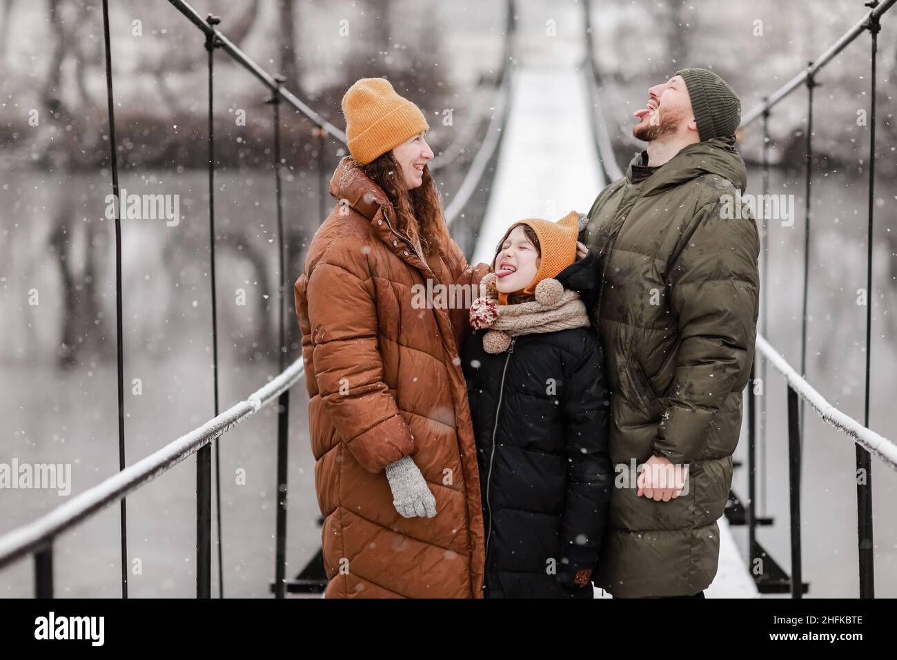 Young mother, father and the little daughter catches snowflakes in a ...