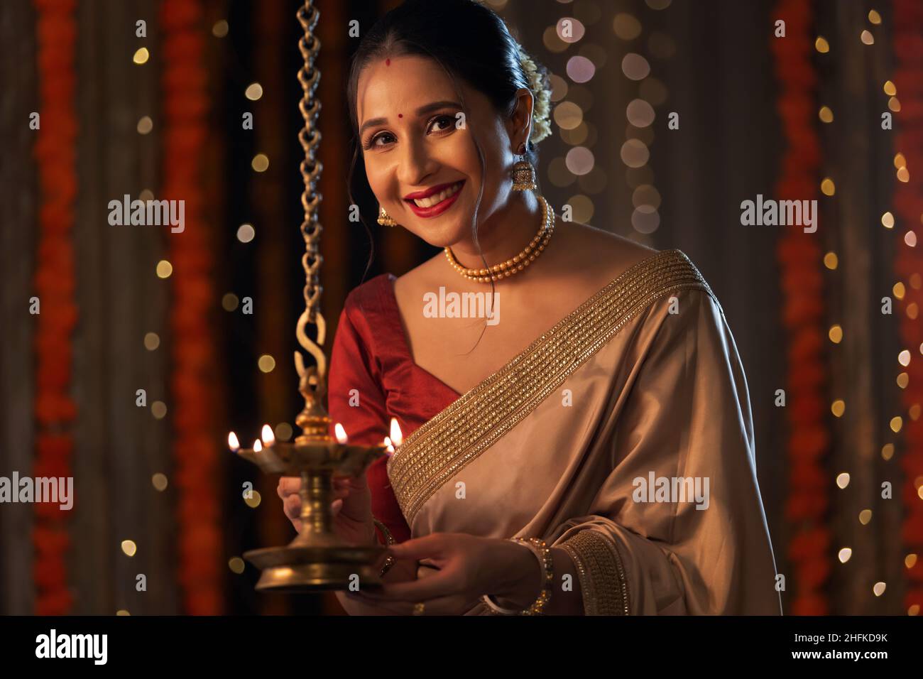 Beautiful Indian woman celebrating Diwali by lightning a lamp with diya ...
