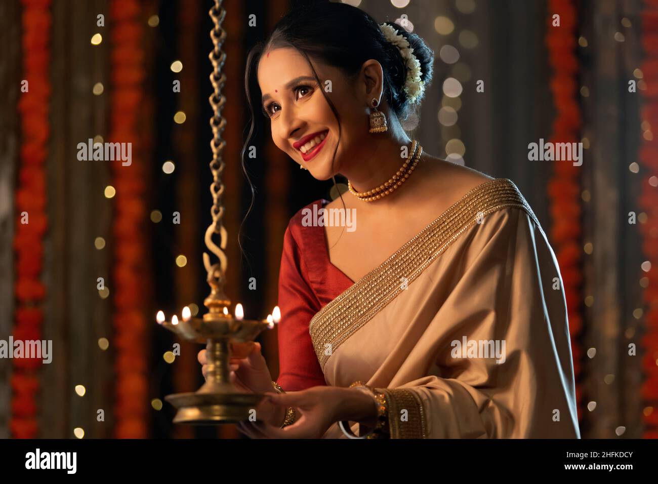 Indian woman celebrating Diwali by lightning a lamp with diya Stock ...