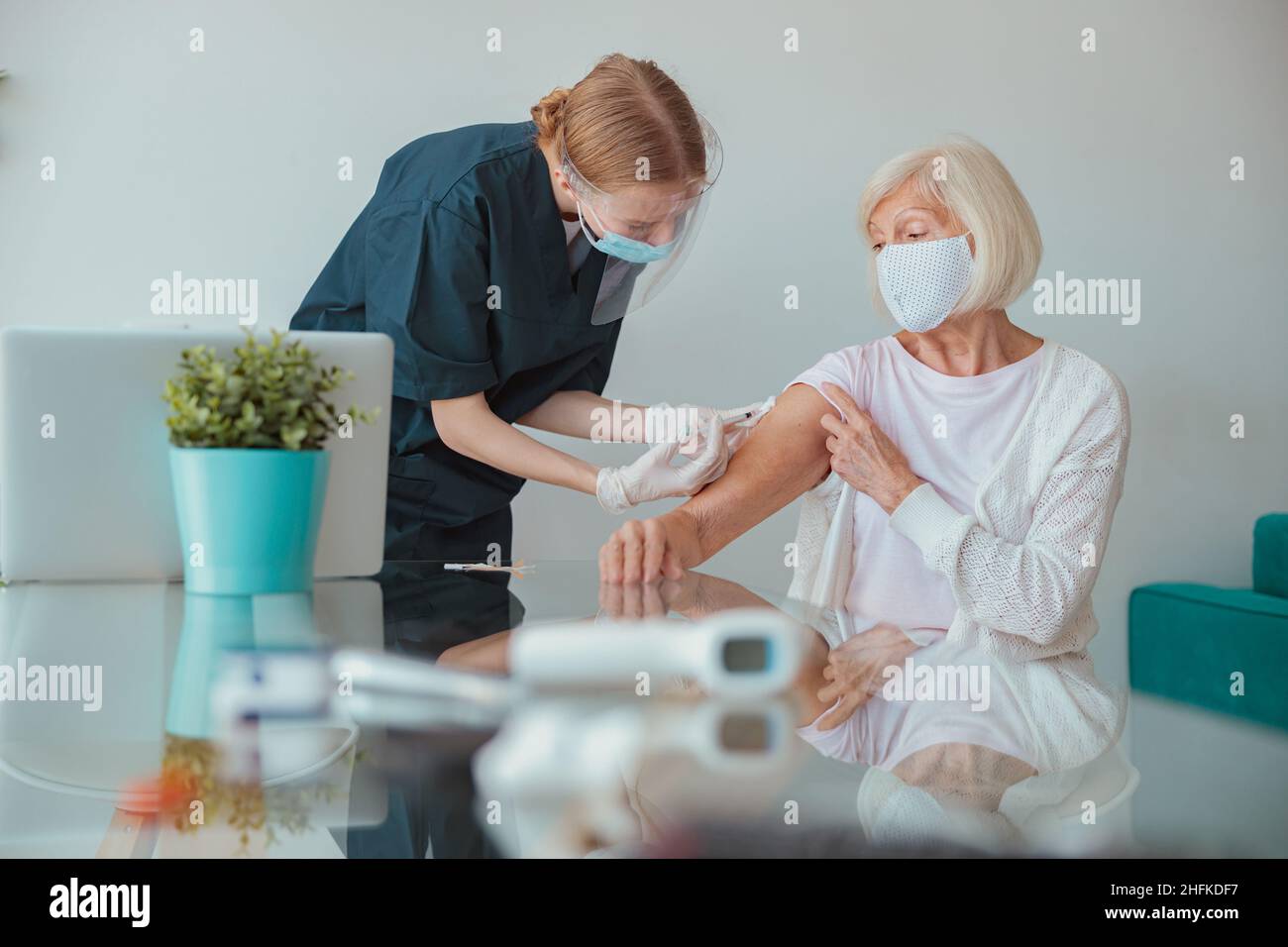 Nurse giving injection to senior woman in living room Stock Photo - Alamy