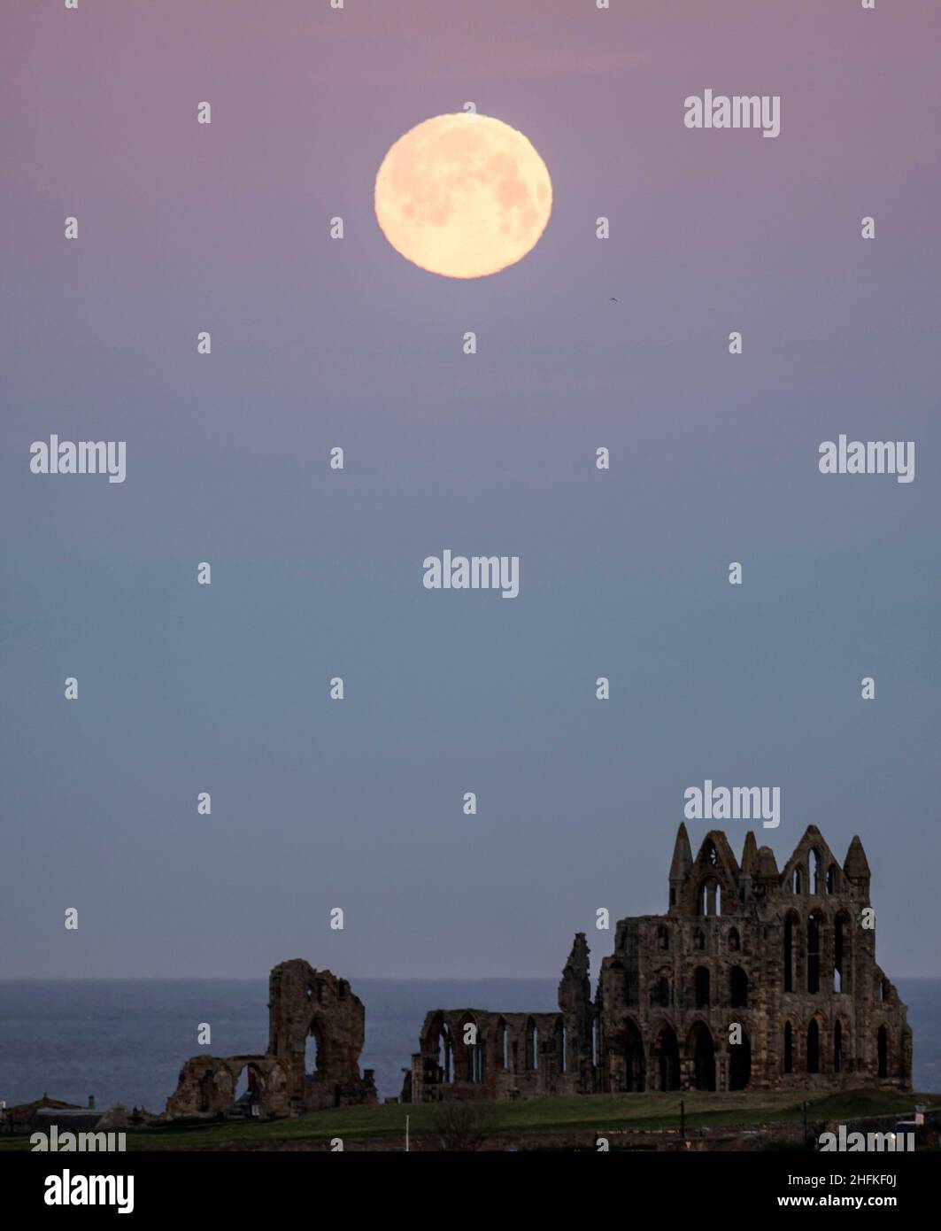 The moon sets behind Whitby Abbey in Yorkshire. The first full moon of ...