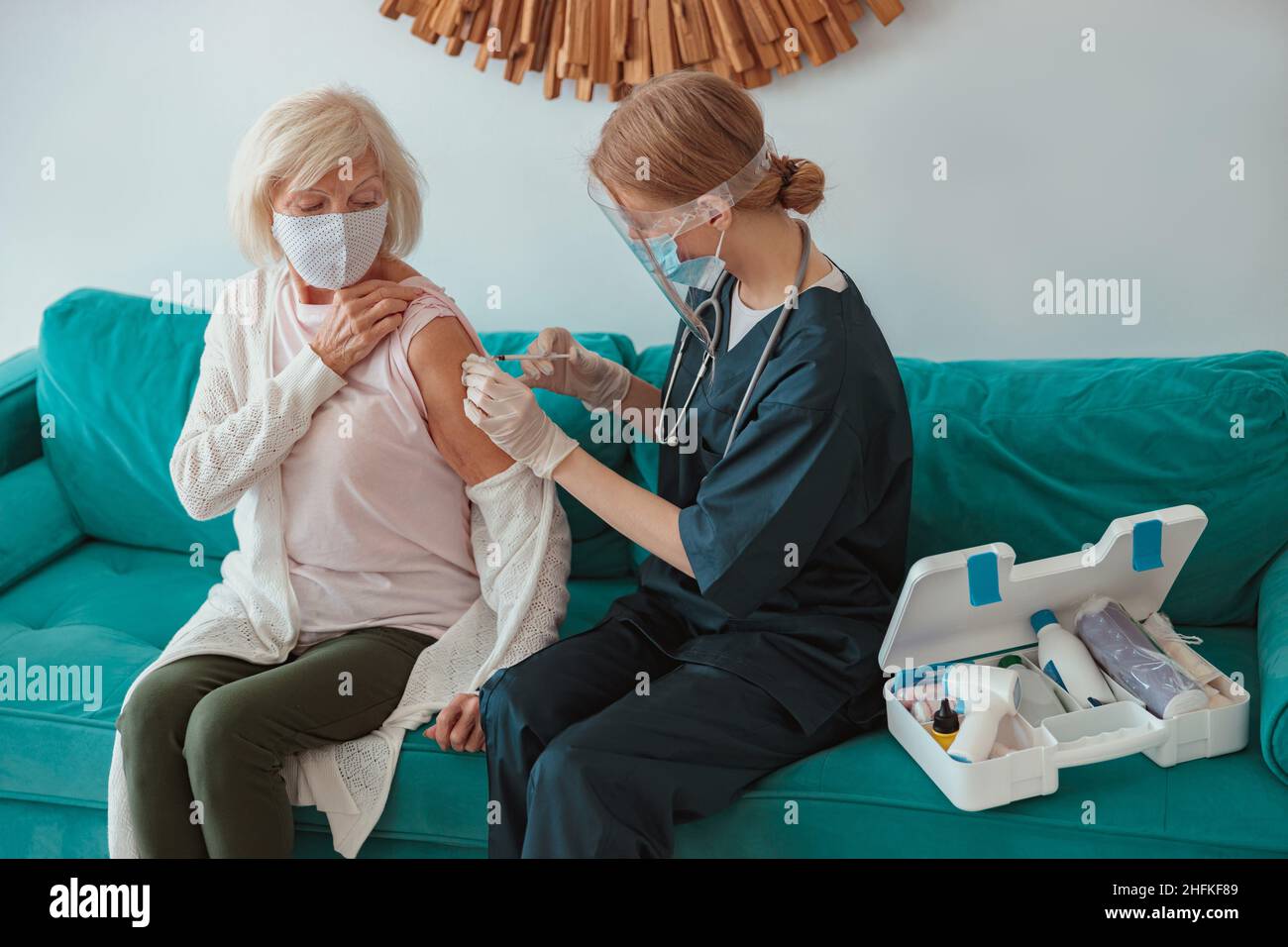 Nurse giving injection to senior woman in living room Stock Photo - Alamy