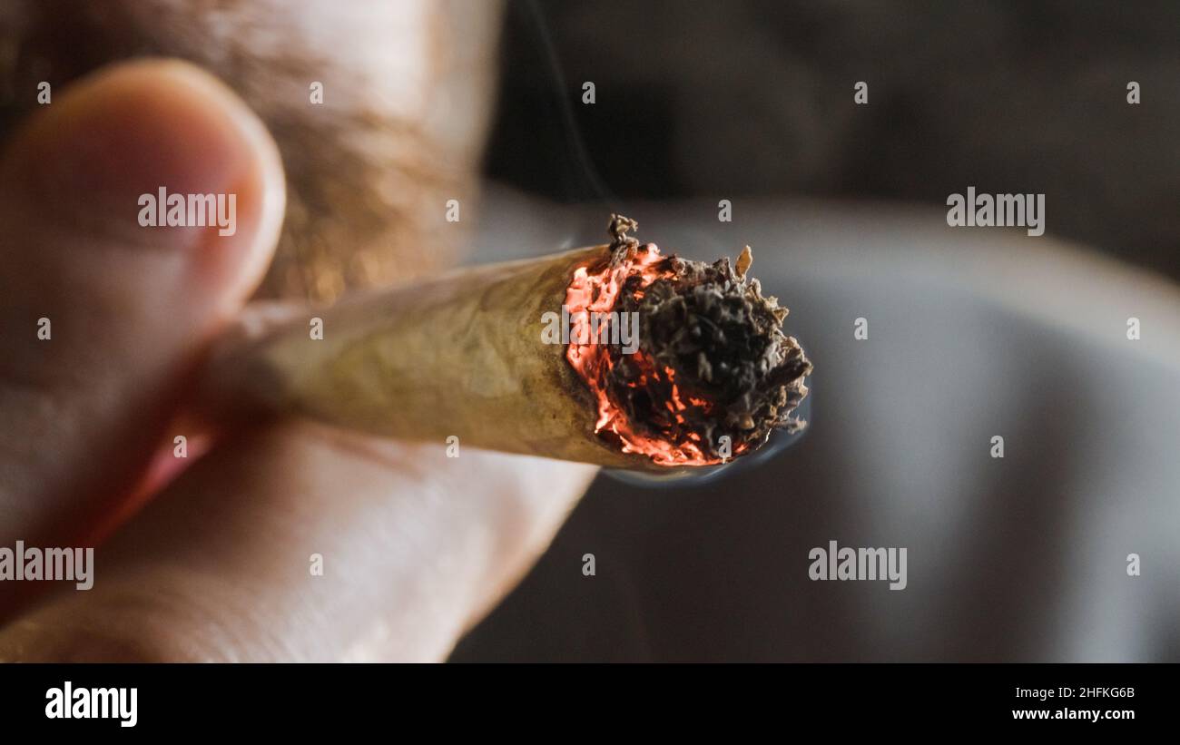 Smoking marijuana joint. Cannabis cigarette burning and a smoke cloud Stock Photo - Alamy