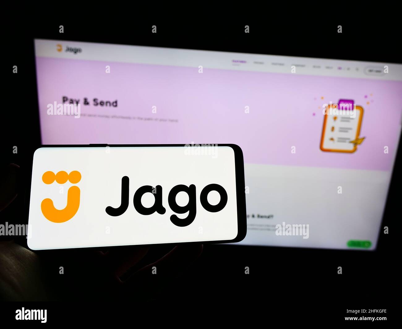 Person holding cellphone with logo of Indonesian financial company PT ...