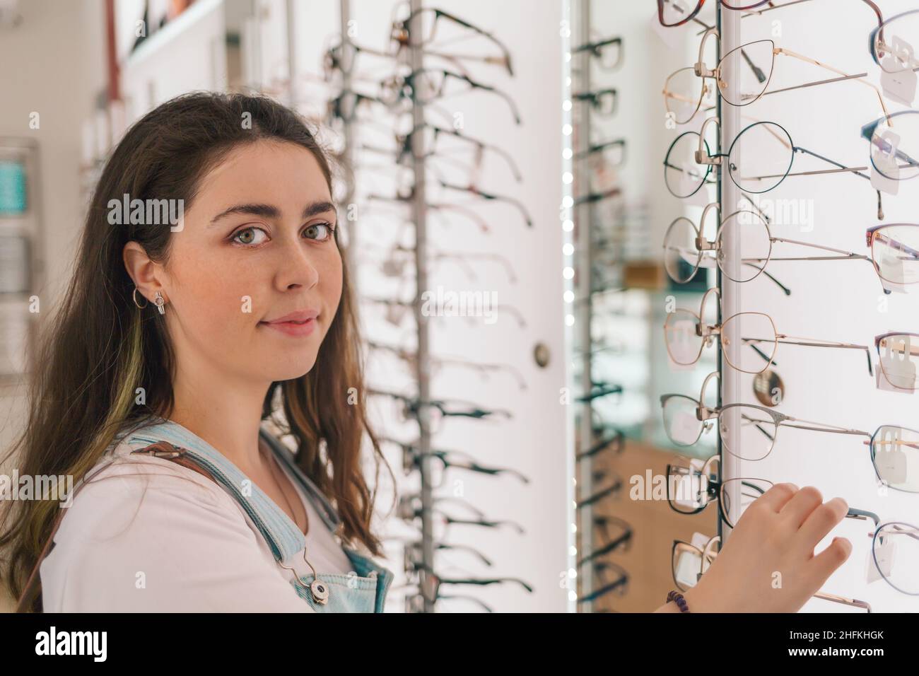 Health and vision. Young beautiful woman choose glasses in optical ...
