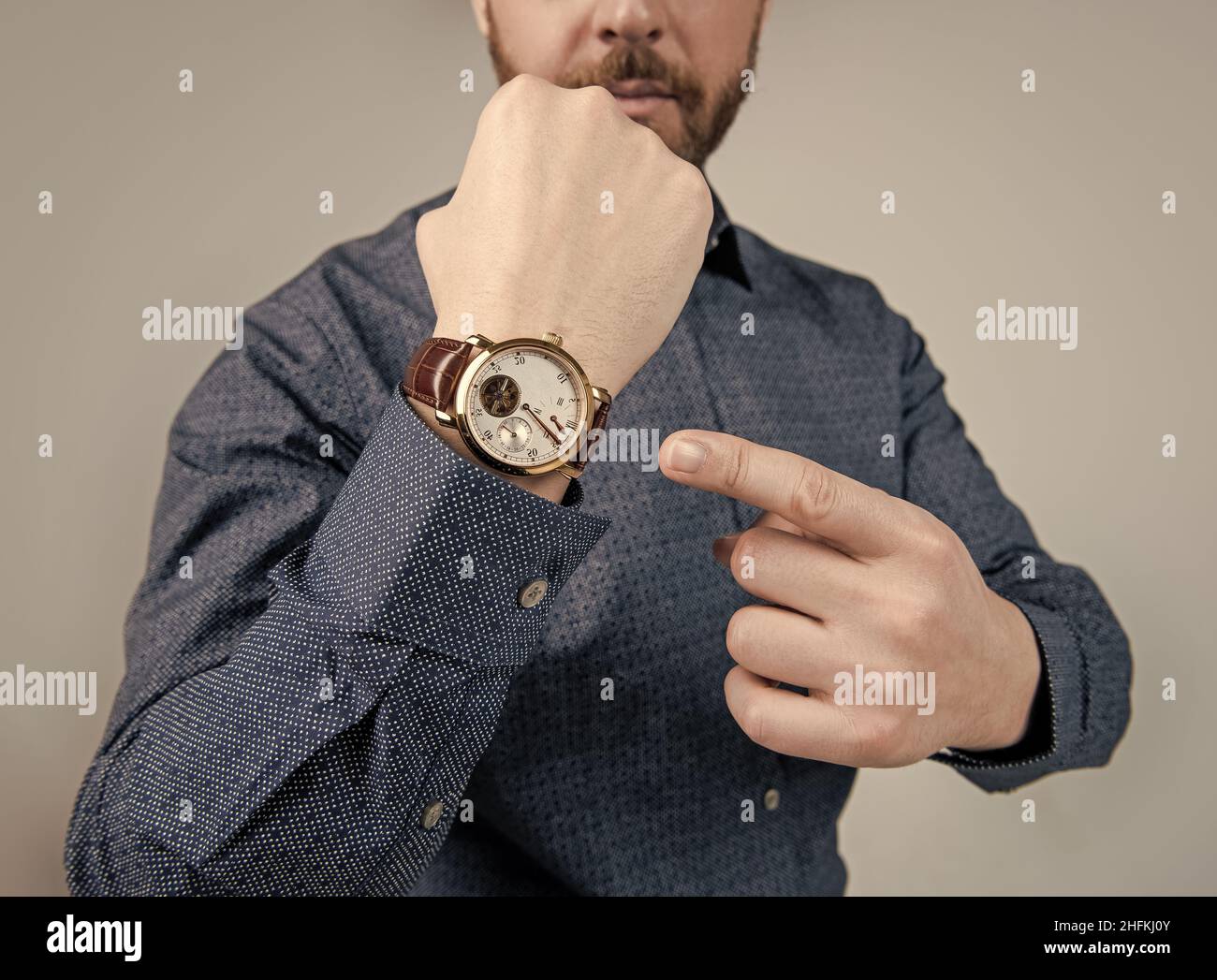 Man cropped view point finger at luxury wrist watch grey background ...