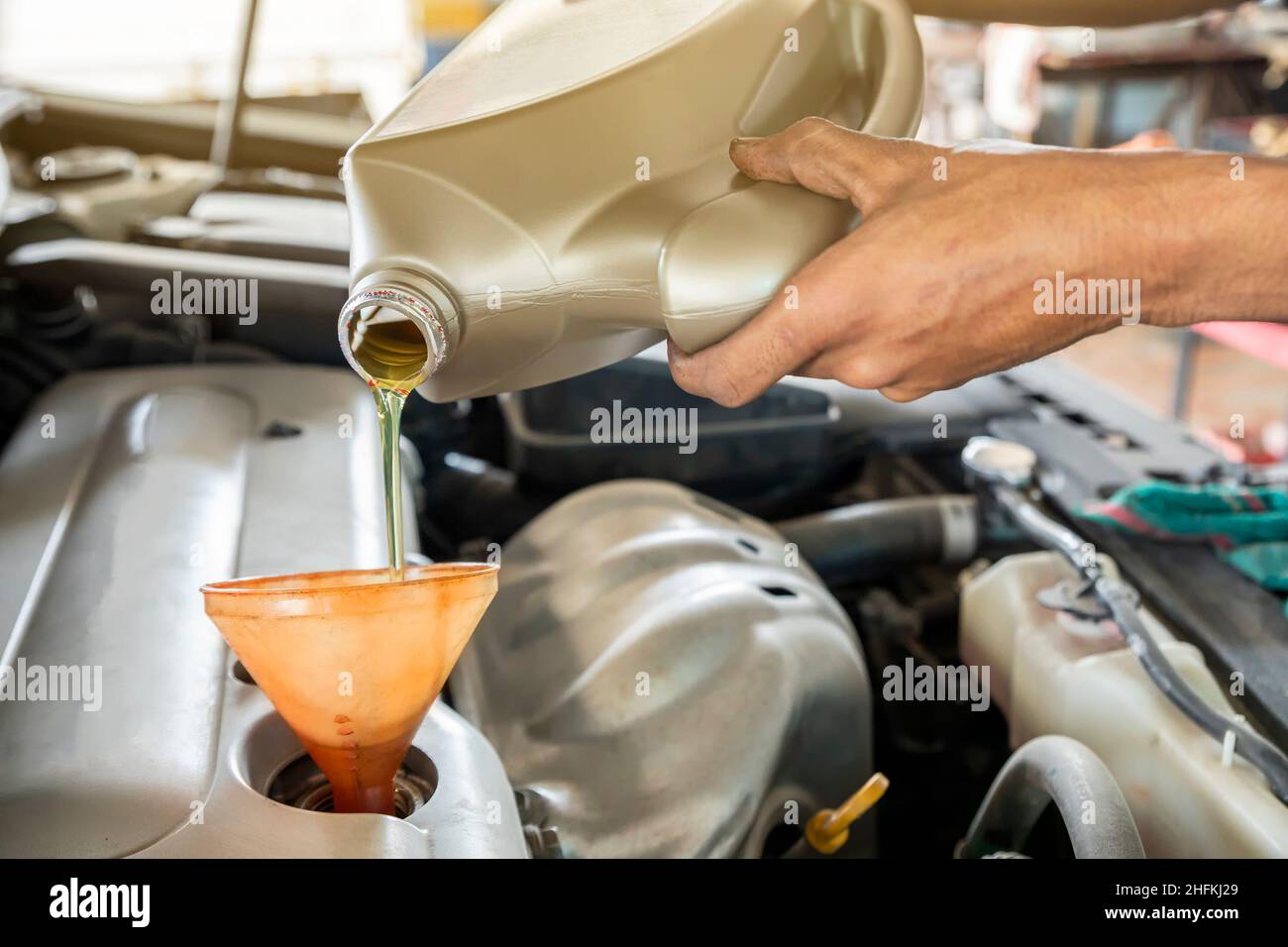 Car mechanic replacing and pouring fresh oil into engine at maintenance ...
