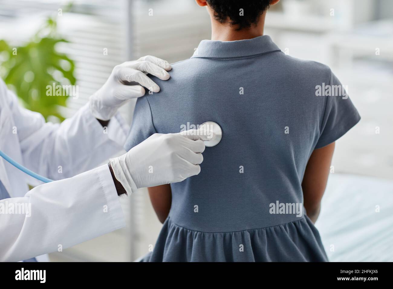Close up doctor using stethoscope while checking breathing of teenage ...