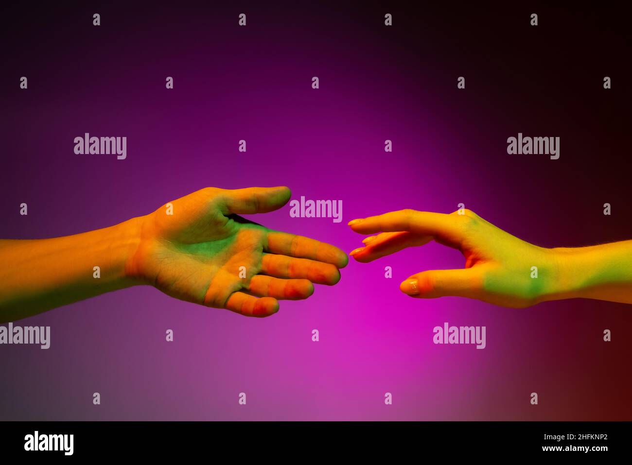 Two human hands trying to touch each other isolated on purple studio ...