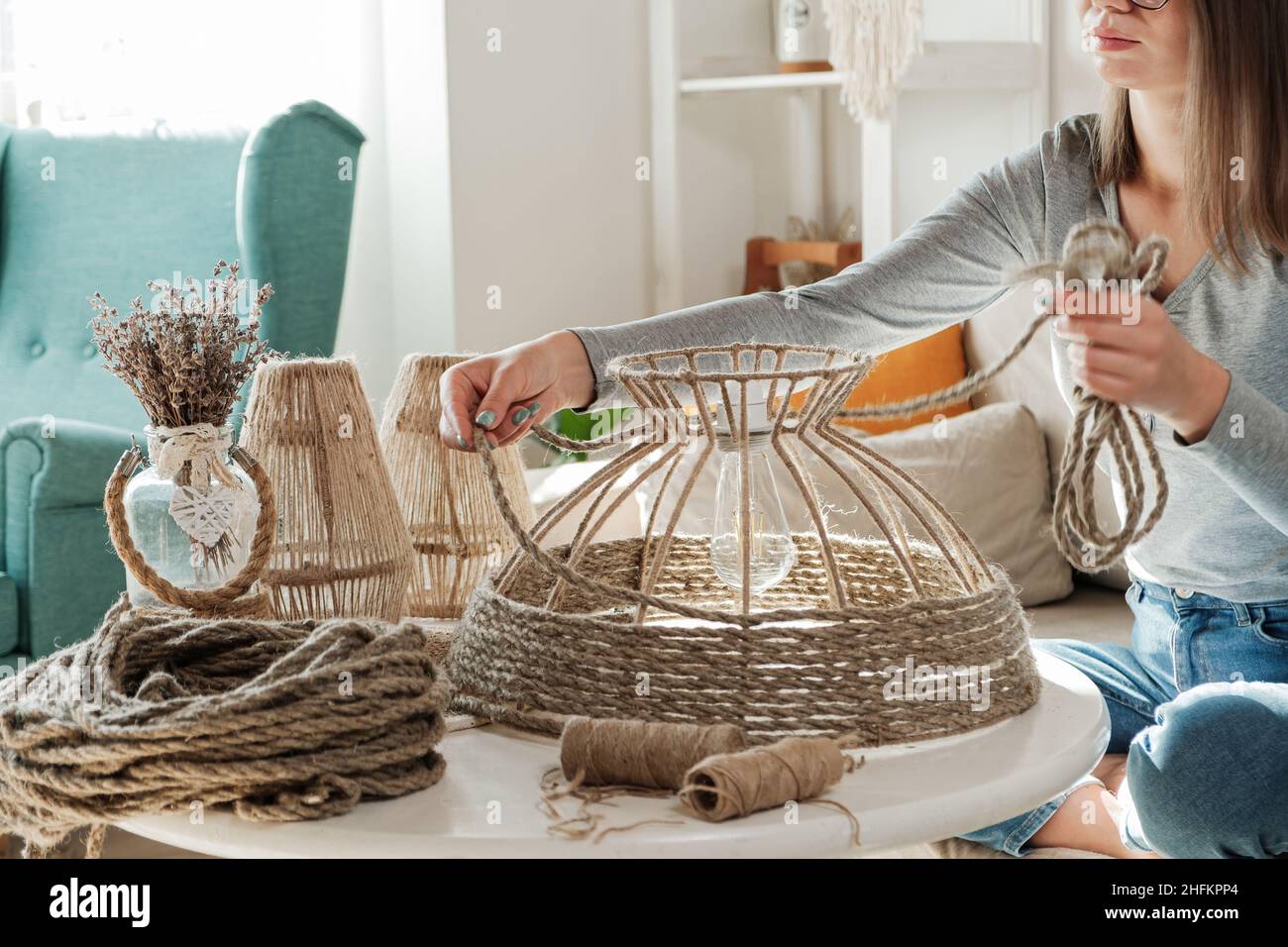 Woman makes handmade diy lamp from jute rope Stock Photo - Alamy