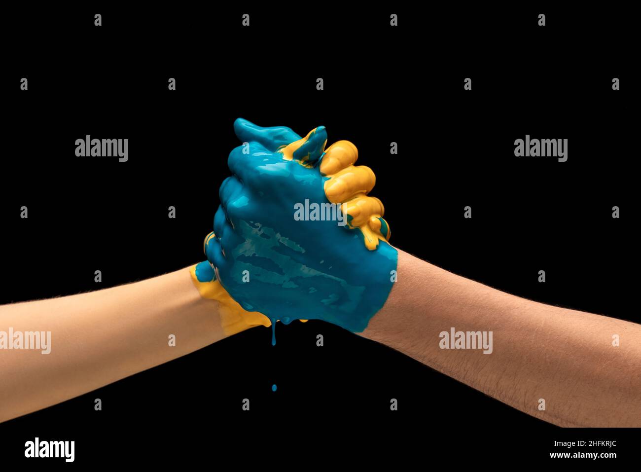 Two painted human hands handshaking isolated on dark studio background ...