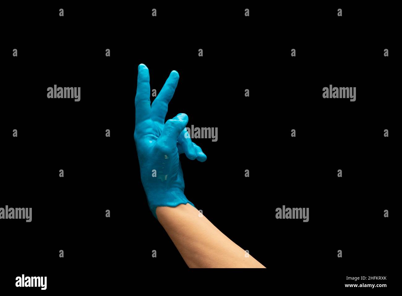 Male hand painted blue gesturing isolated on dark studio background ...