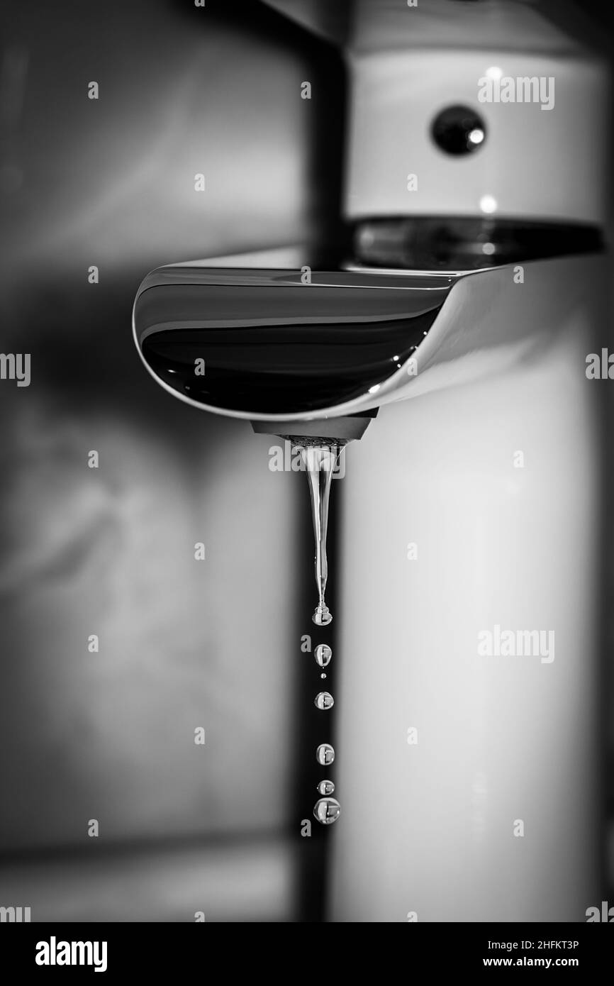 Clear water drops falling from the faucet. Contrast black and white ...