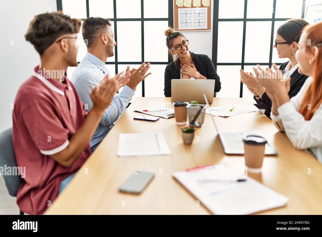 Group of business workers smiling and clapping to partner at the office ...