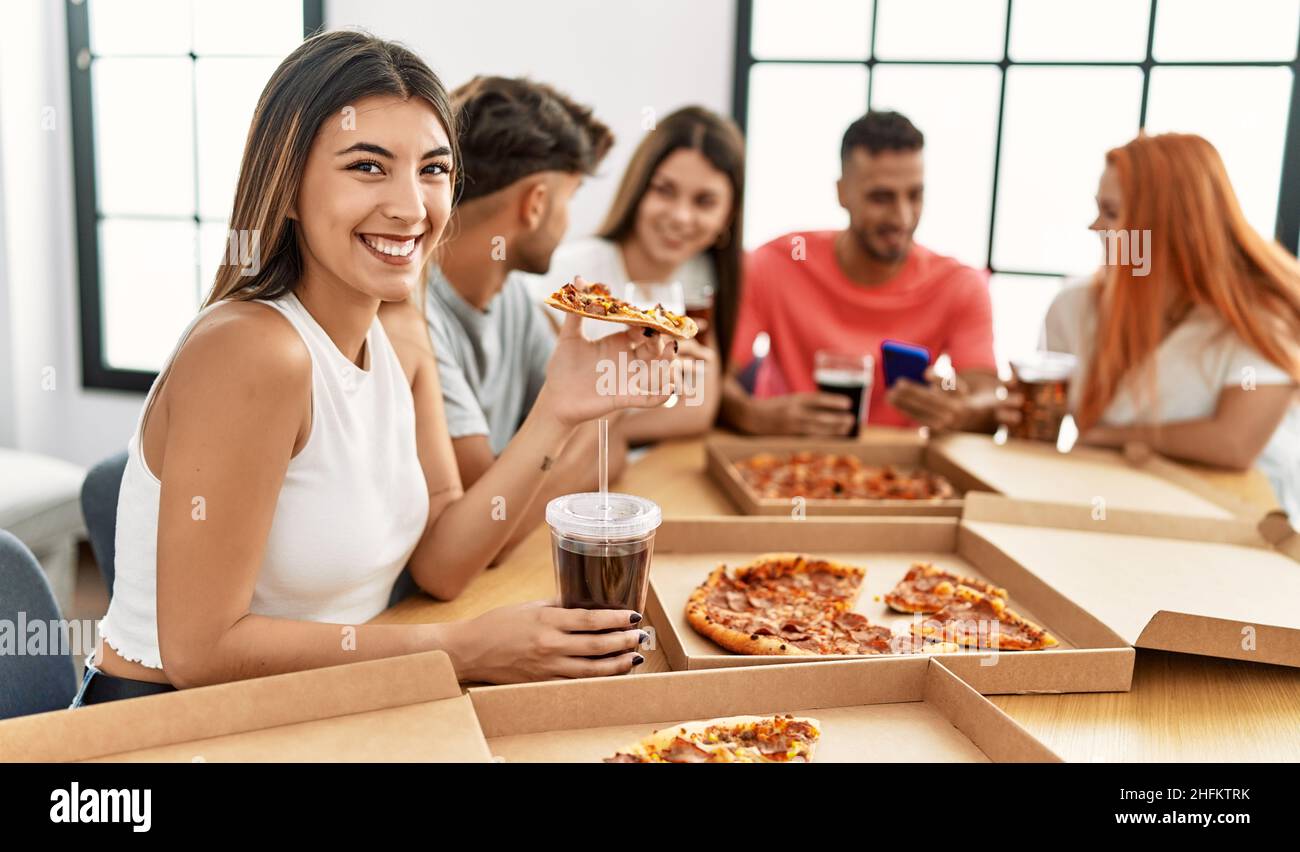 Group of young people smiling happy eating italian pizza sitting on the ...