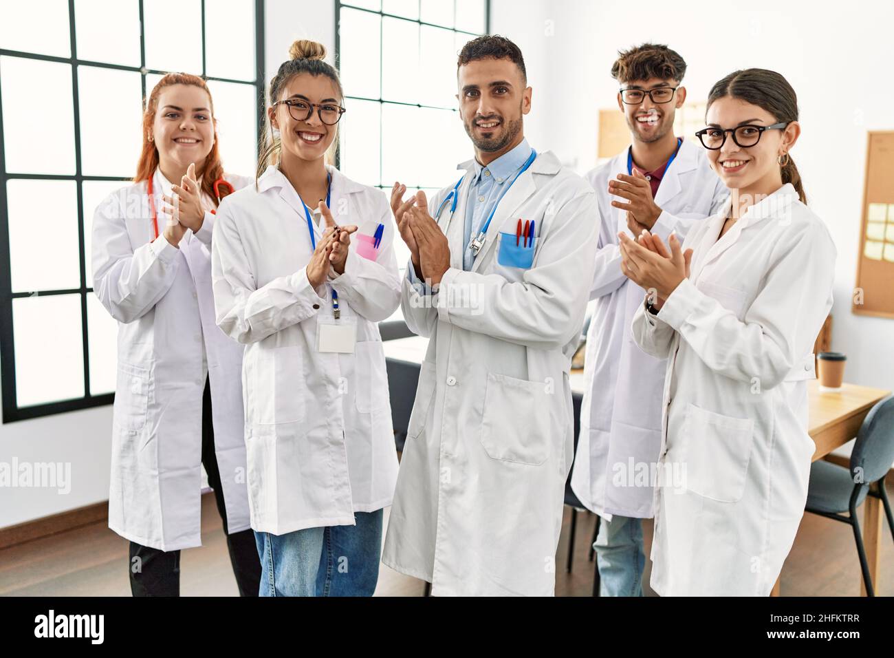 Group of young doctor smiling happy and clapping standing at the clinic ...