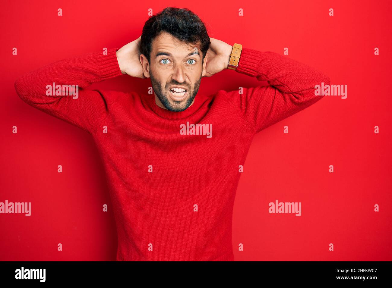 Handsome man with beard wearing casual red sweater crazy and scared ...