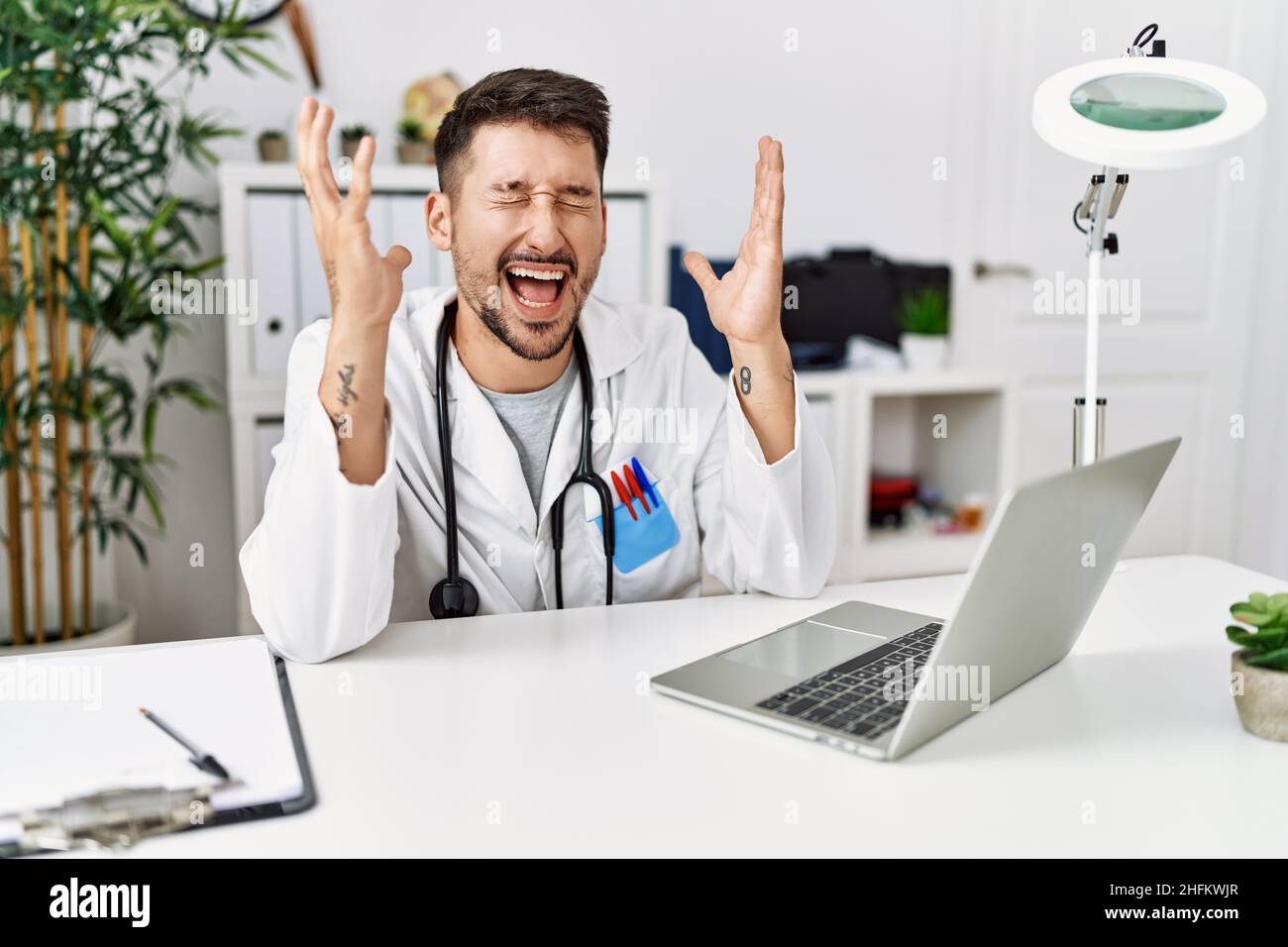 Young doctor working at the clinic using computer laptop celebrating ...