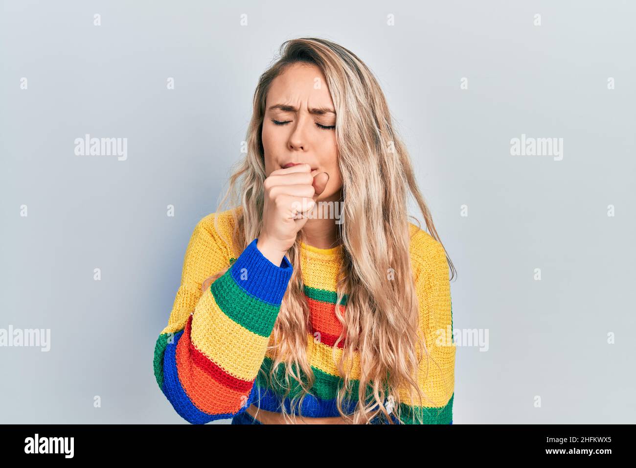 Beautiful young blonde woman wearing colored sweater feeling unwell and ...