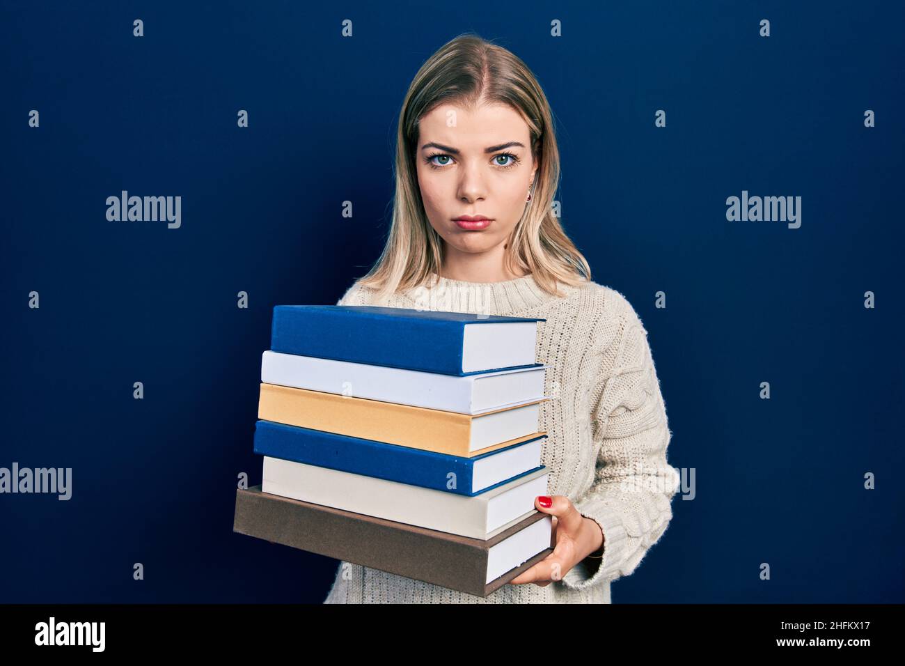 Beautiful caucasian woman holding a pile of books depressed and worry ...