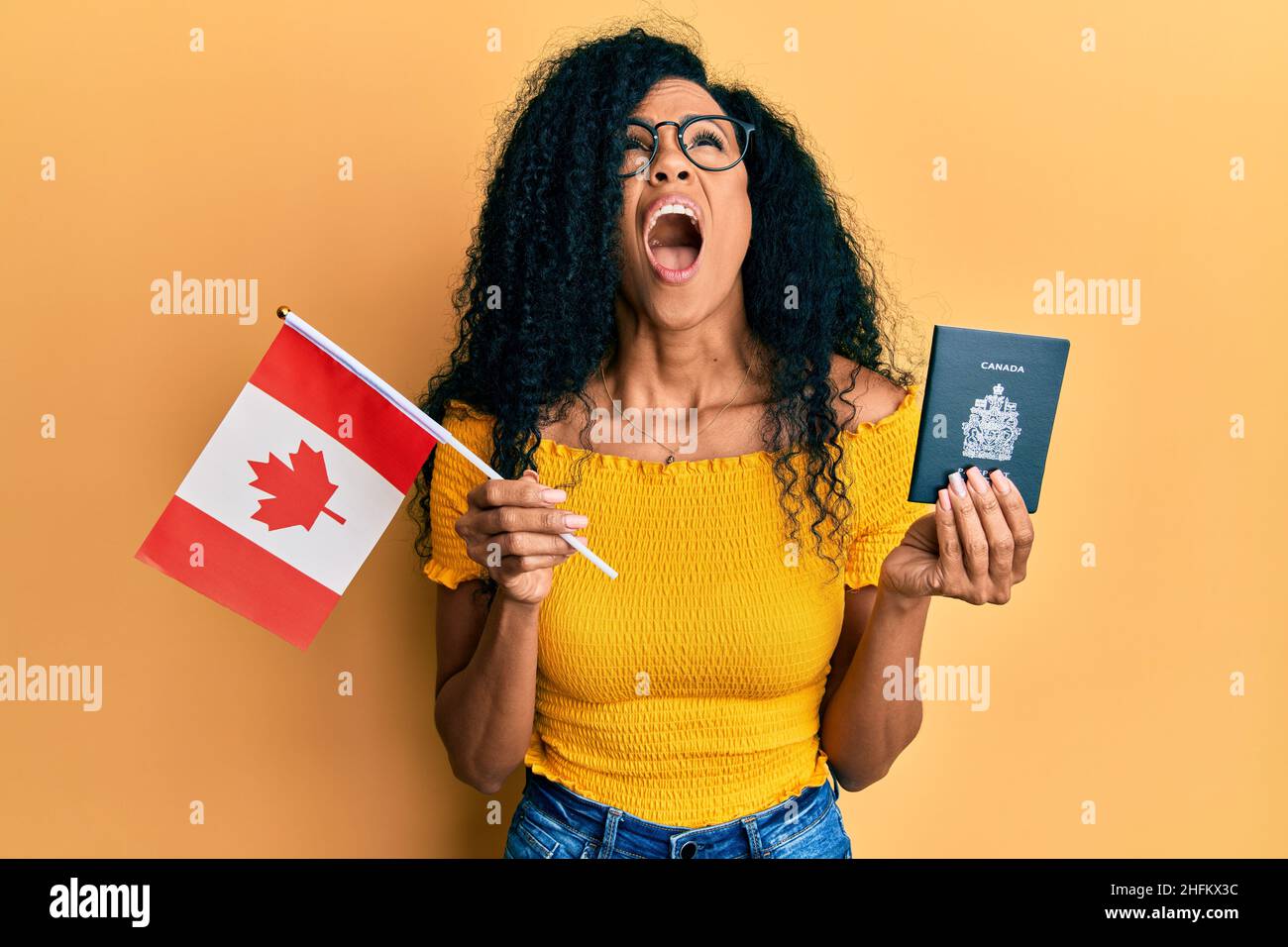 Middle age african american woman holding canada flag and passport ...