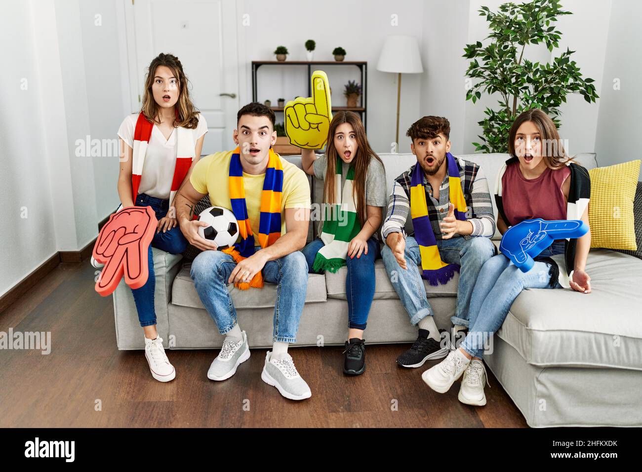 Group of young people watching football game wearing team scarf ...