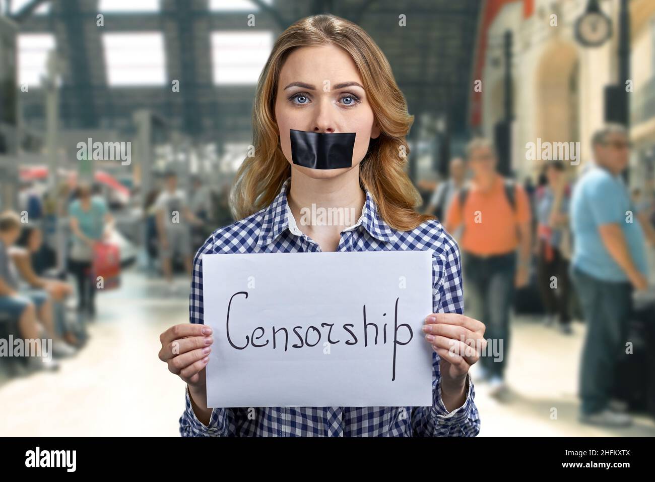 Young caucasian woman with taped mouth holding banner with inscription ...