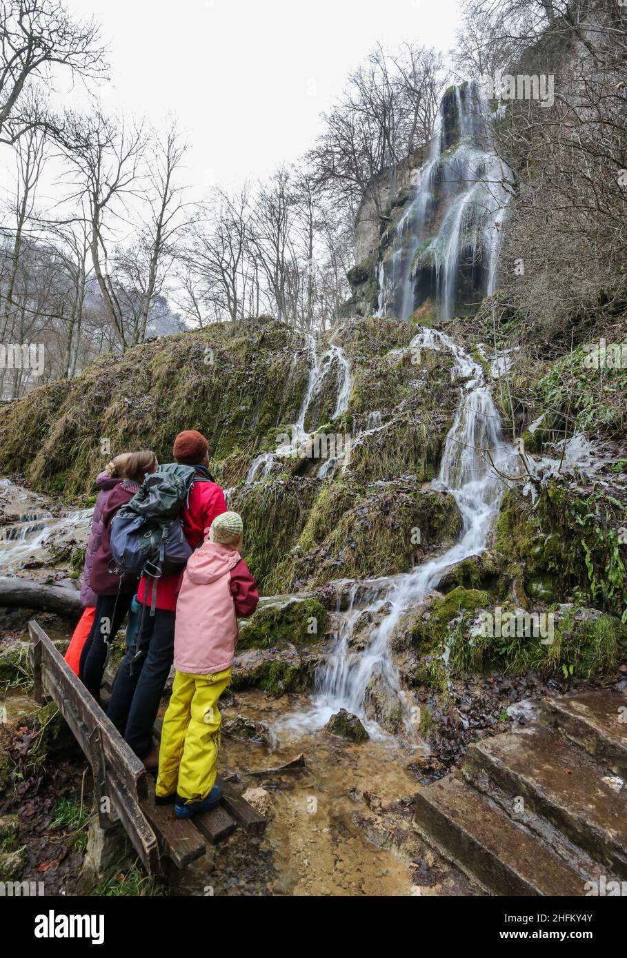 Bad Urach, Germany. 16th Jan, 2022. Hikers stand below the waterfall ...