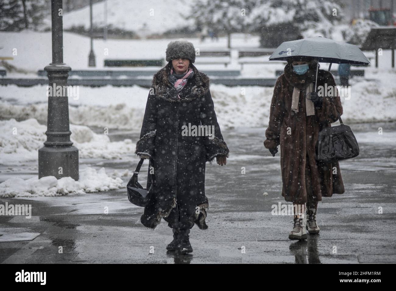 Winter in Serbia: women with an umbrella and face mask during a snow ...