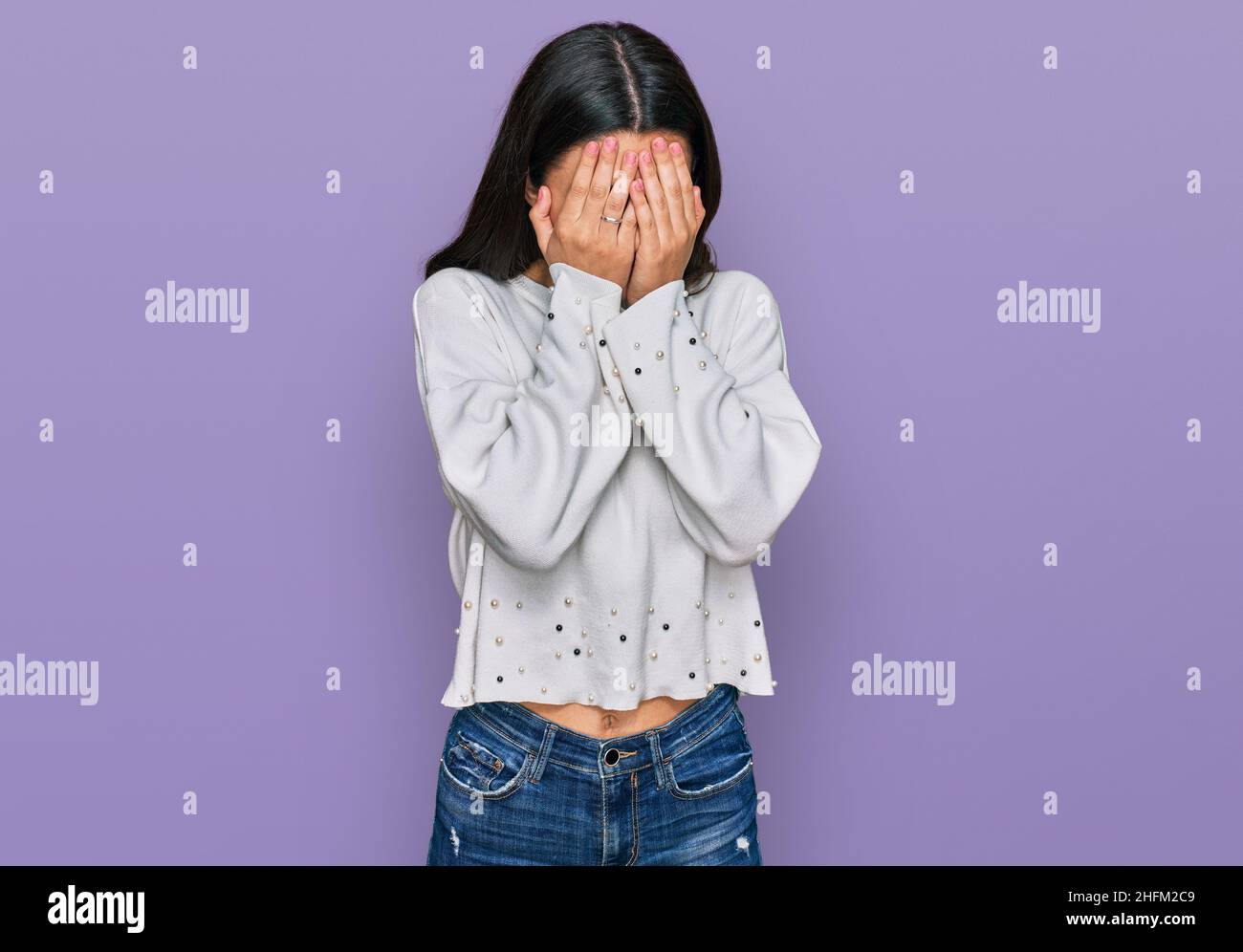 Young hispanic girl wearing casual clothes with sad expression covering ...